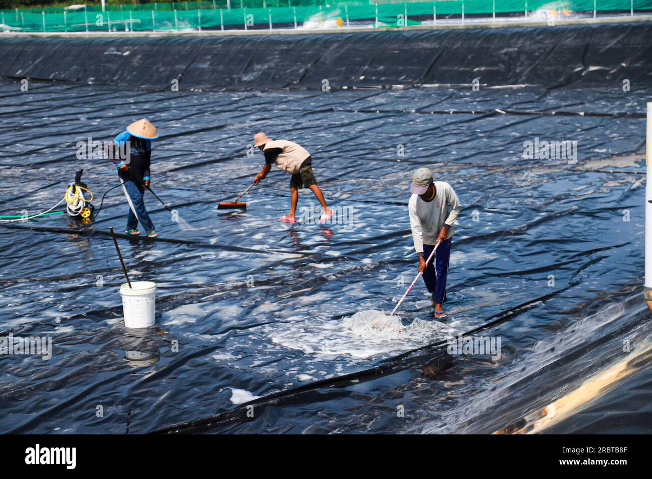 Several pond farmers are cleaning LDPE plastic ponds before starting to ...