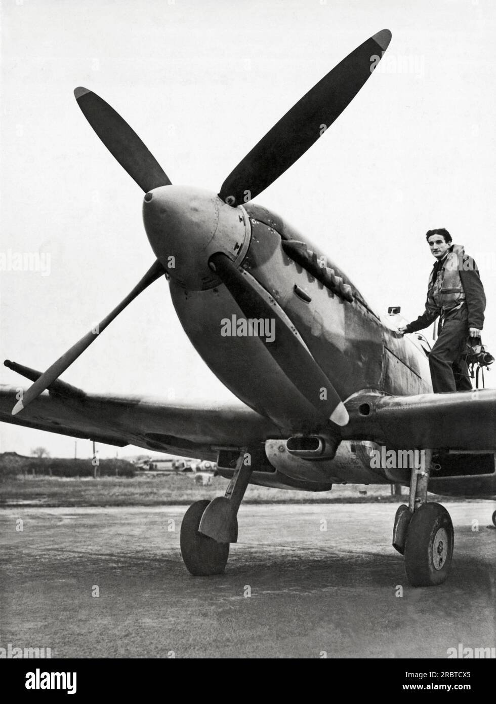 England: c. 1940 An R.A.F.pilot stands next to a Spitfire aircraft with ...