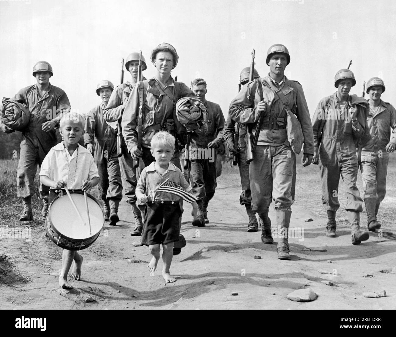 Europe: 1944 Two barefoot boys playing a drum and waving a U.S. Flag ...