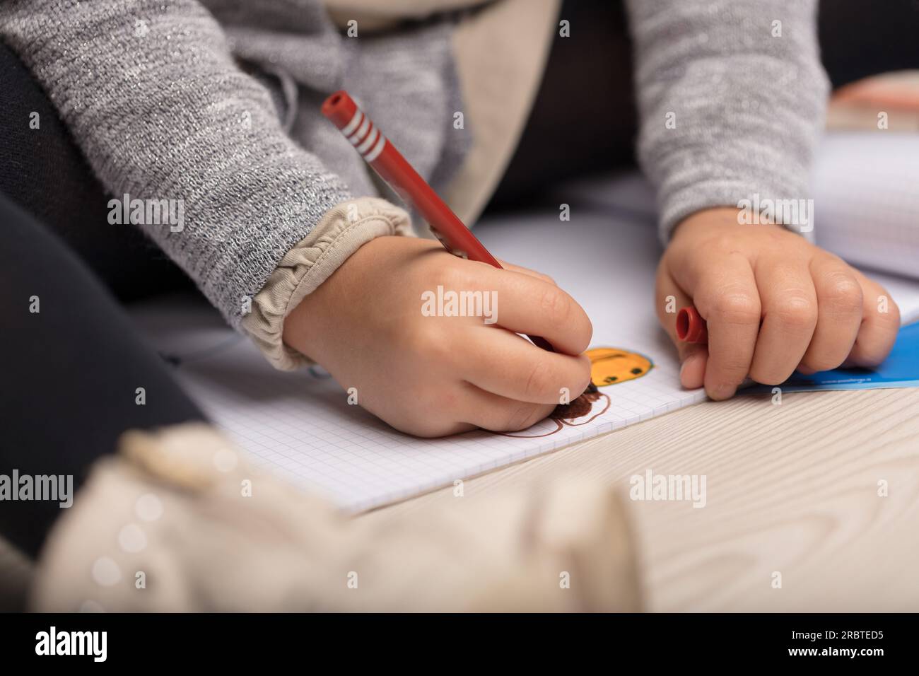 The tiny hands of a girl are in focus, drawing maybe a bee, an insect ...