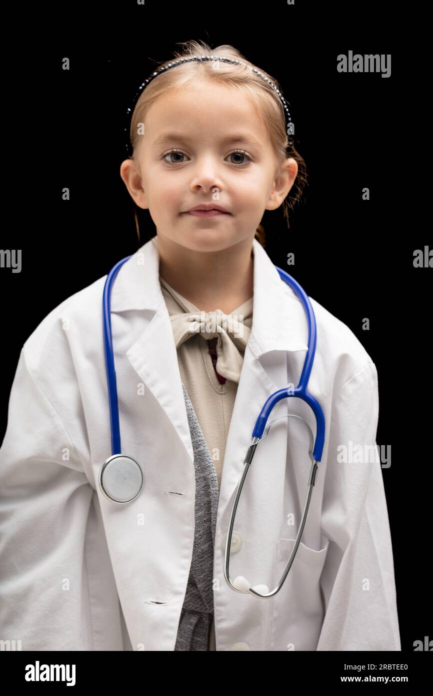 Small girl plays doctor, half-body portrait on black background. She ...