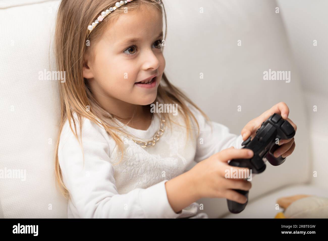 At home, a little girl delights in playing video games, guided by her ...