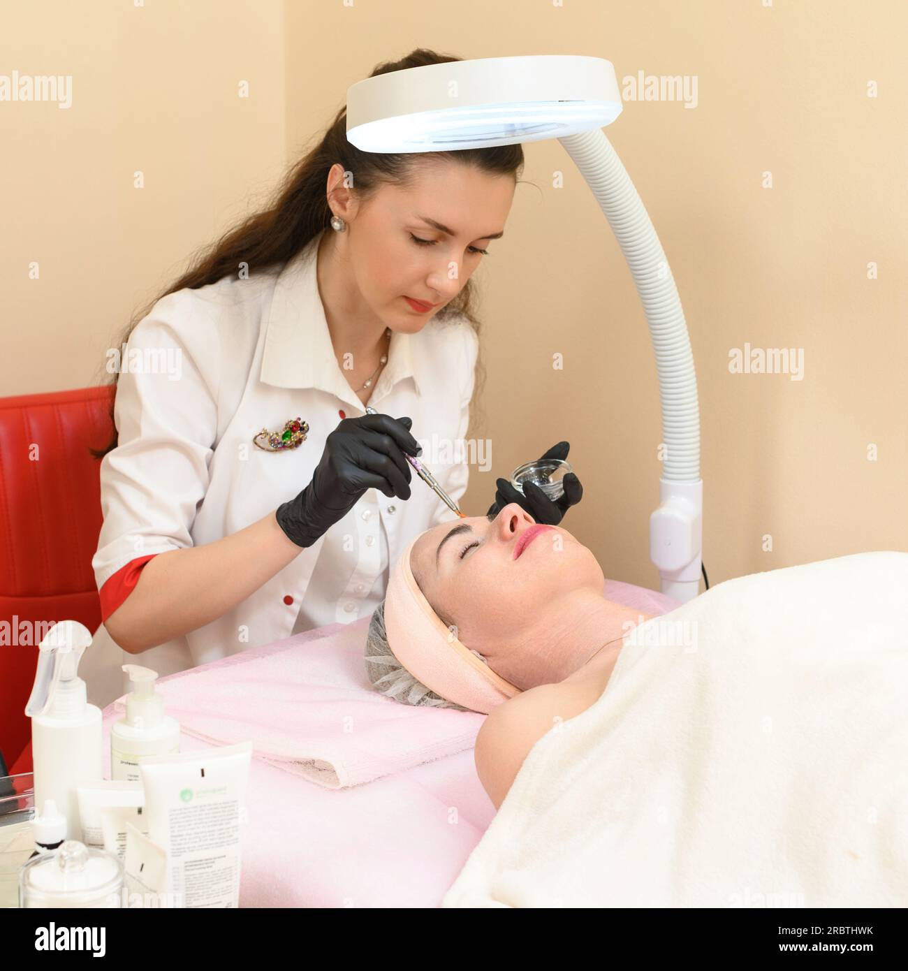 Applying the rejuvenation drug with a brush, the beautician performs ...