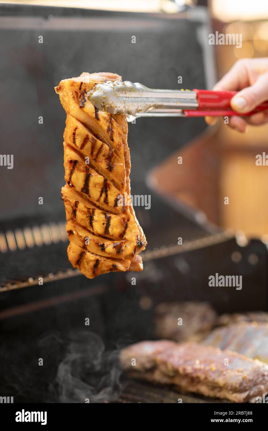 BBQ meat concept. Barbecue pork ribs. Man flips grilled marinated ribs ...
