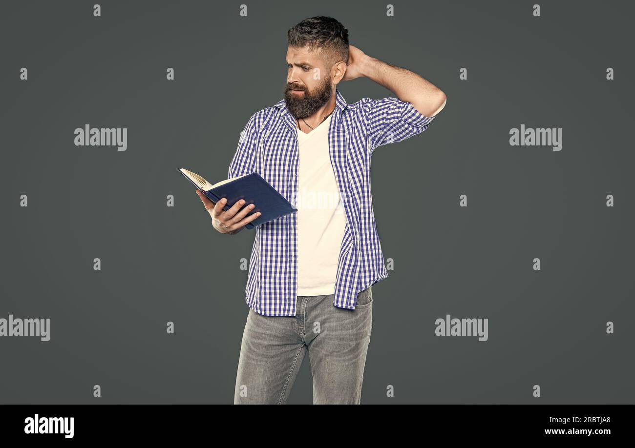 puzzled bearded man reading book on grey background Stock Photo - Alamy