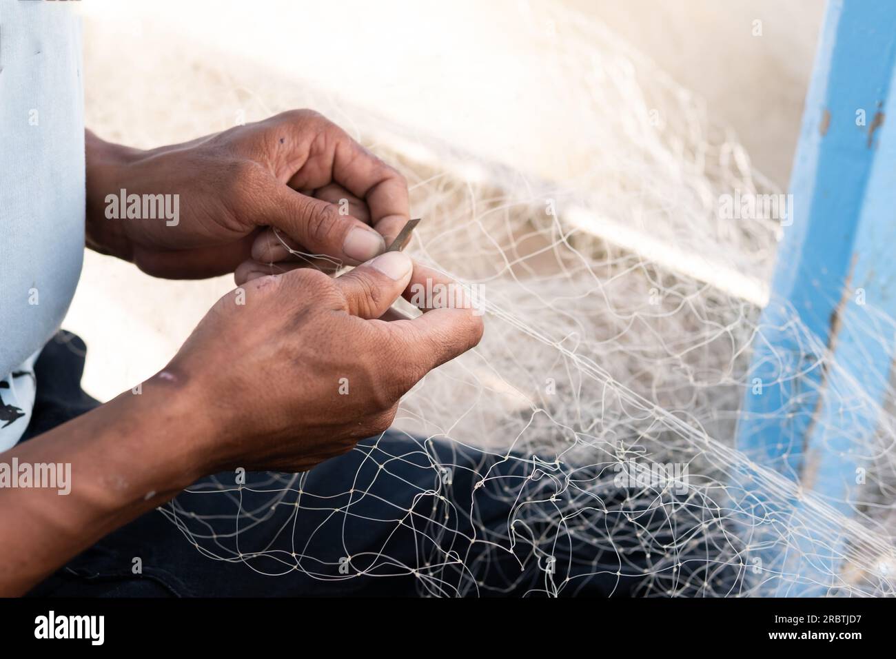 The man is repairing a fishing net on a boat in a village, Indonesia ...