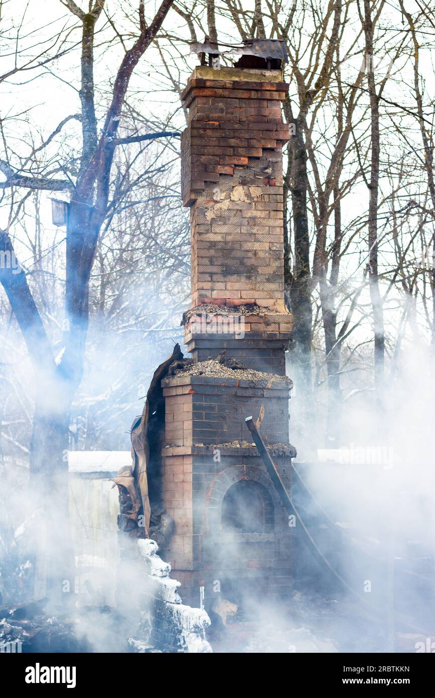 Remains of a house after a fire. The brick tube of the stove is ...