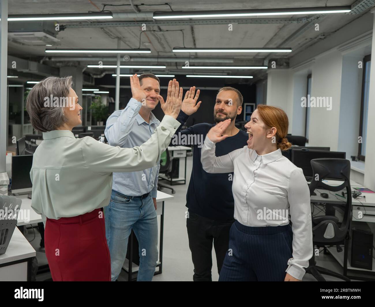 Four co-workers give a high five in the office Stock Photo - Alamy