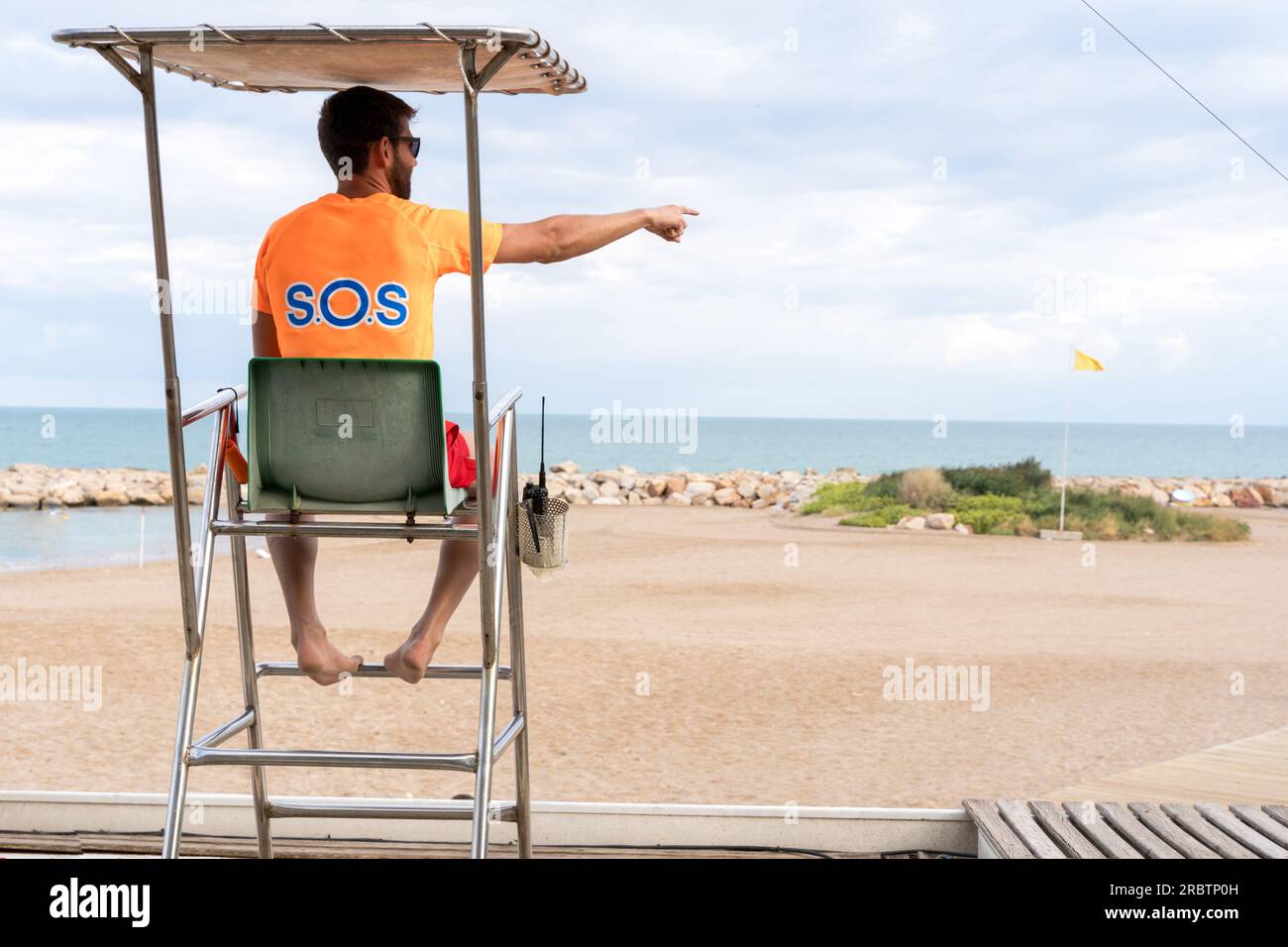 Photo with copy space of the rear view of a lifeguard sitting on a ...