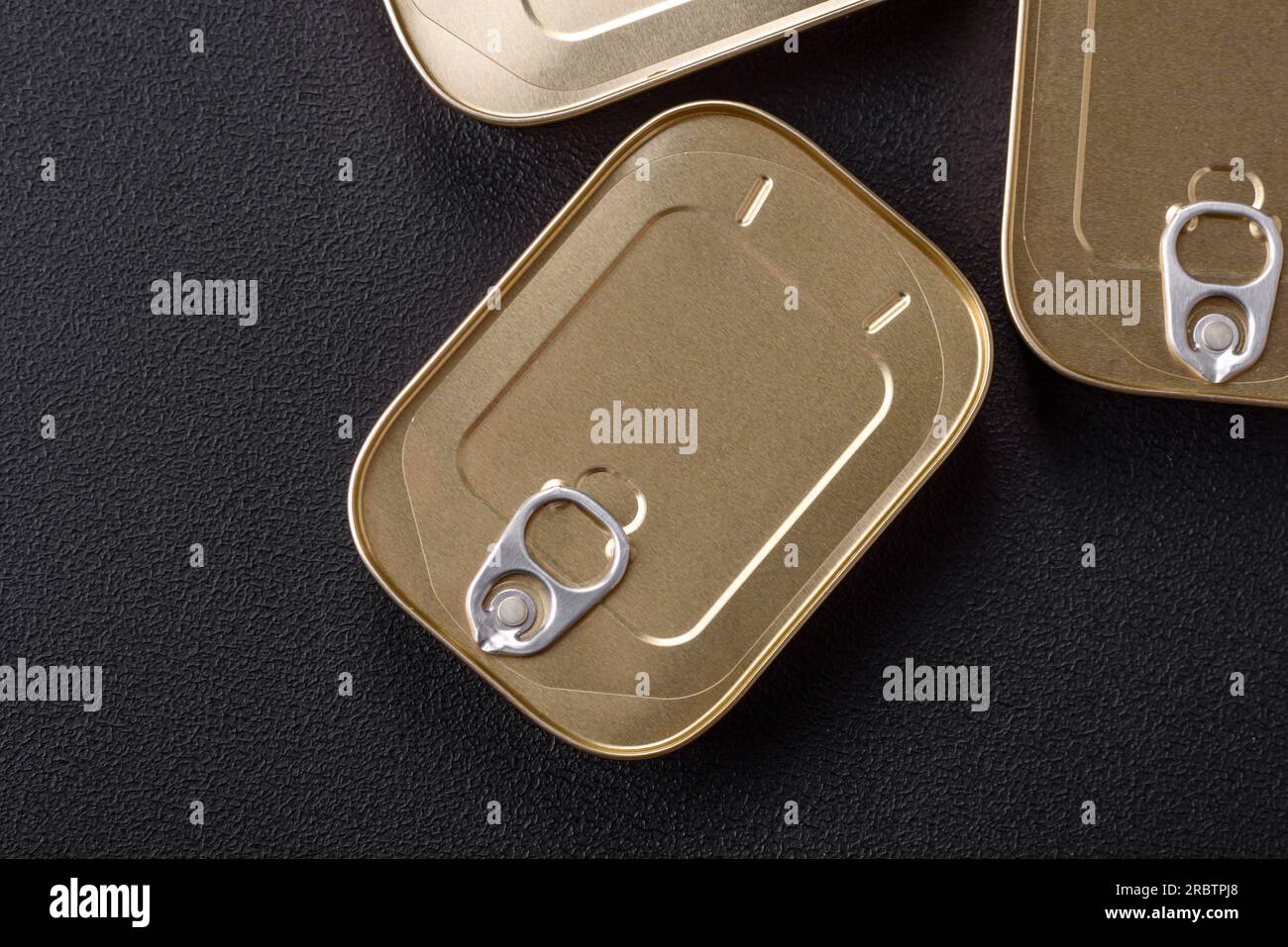 Tin or aluminum rectangular can of canned food with a key on a dark ...