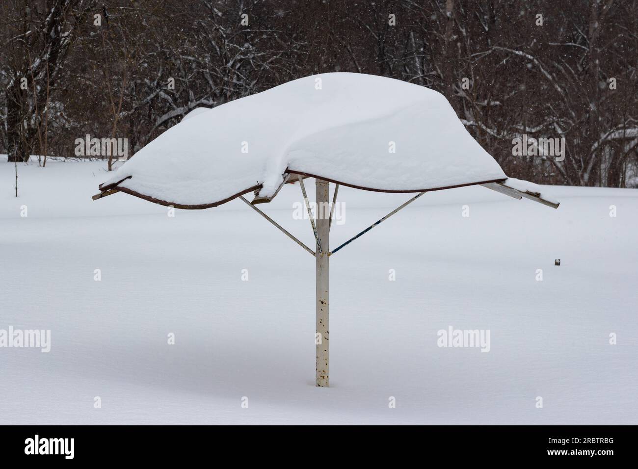 Beach umbrella heavily covered with snow during snowfall in winter ...