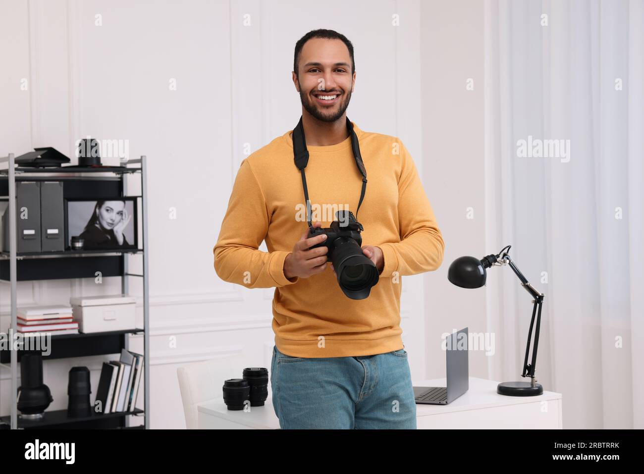 Young professional photographer with camera in modern photo studio ...
