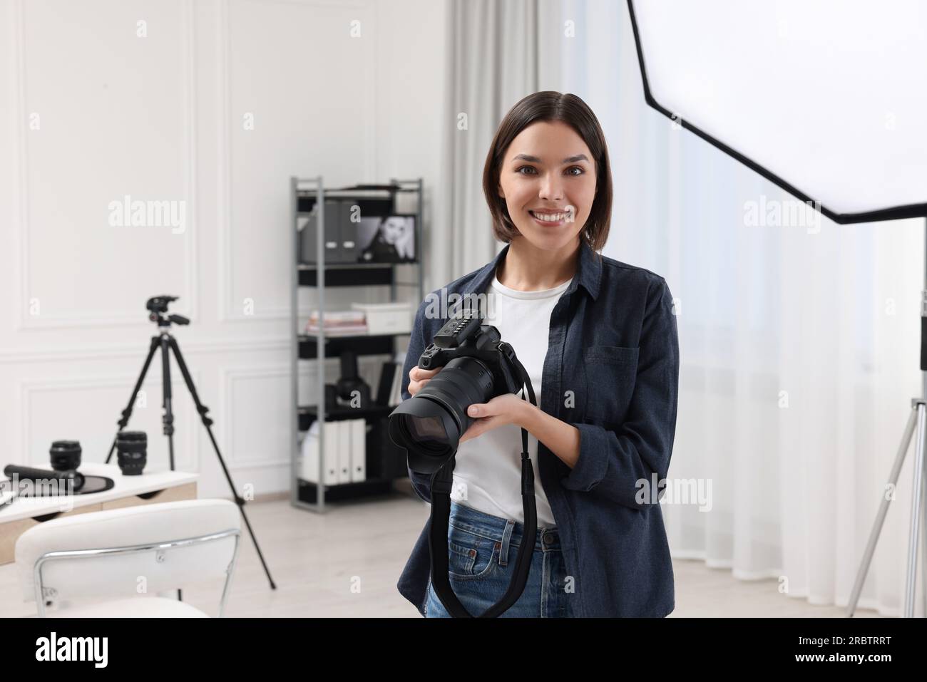 Young professional photographer with camera in photo studio, space for ...