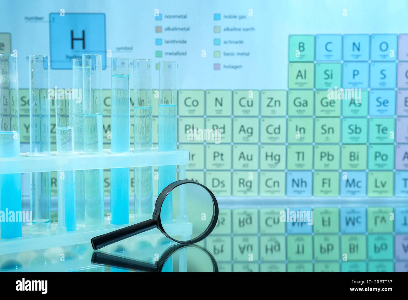 Magnifying glass and test tubes in rack on mirror surface against ...