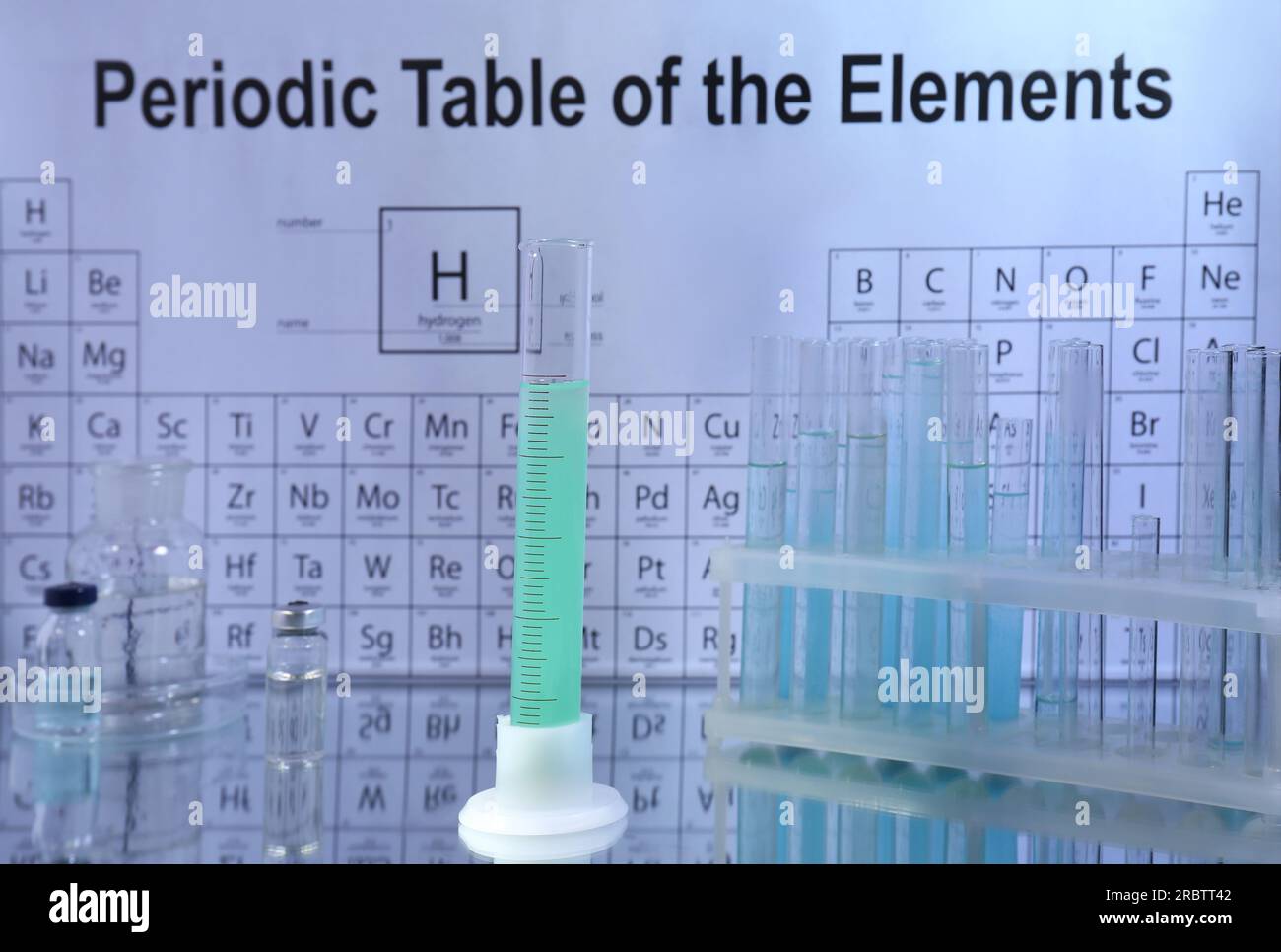 Graduated cylinder, bottles and test tubes in rack on mirror surface ...