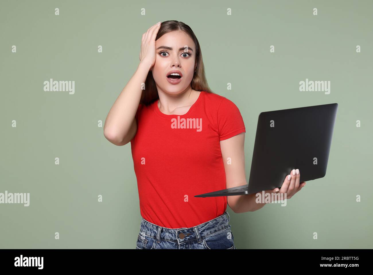 Emotional woman with laptop on pale green background Stock Photo - Alamy
