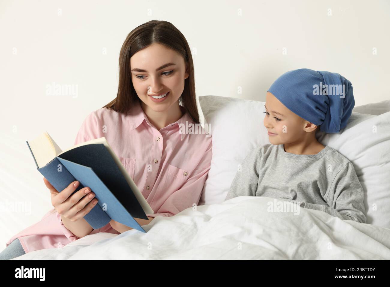 Childhood cancer. Mother and daughter reading book in hospital Stock ...