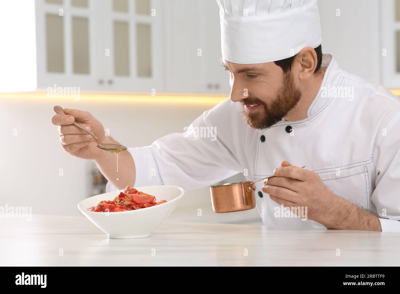 Professional chef pouring sauce into delicious spaghetti at marble ...