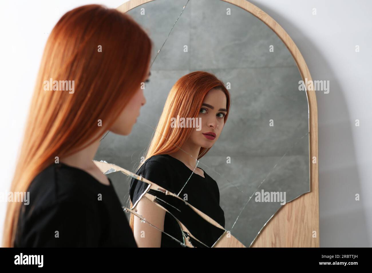 Mental problems. Depressed young woman looking at herself in broken ...