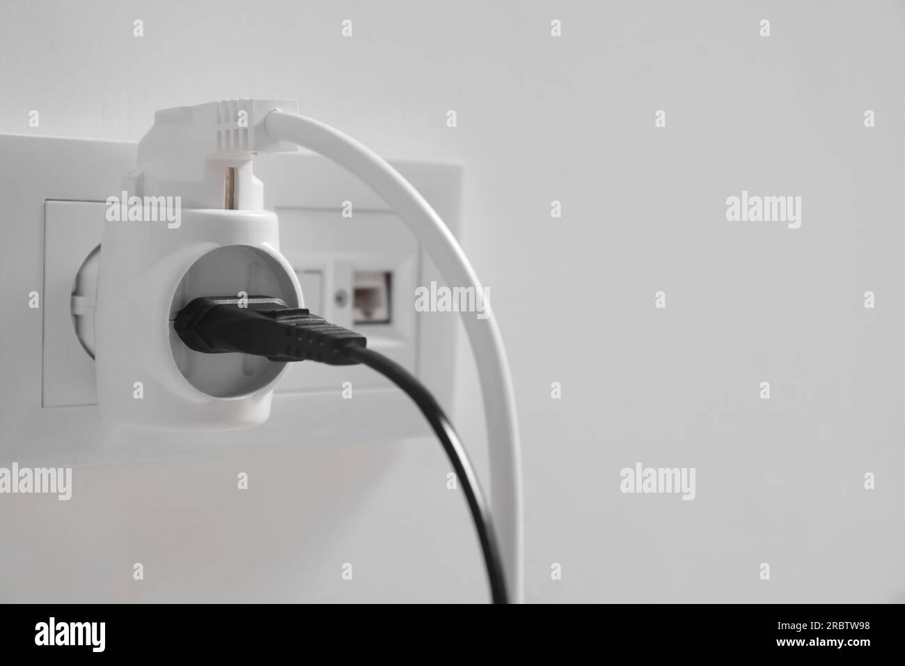 Different electrical power plugs in socket on light wall, closeup ...