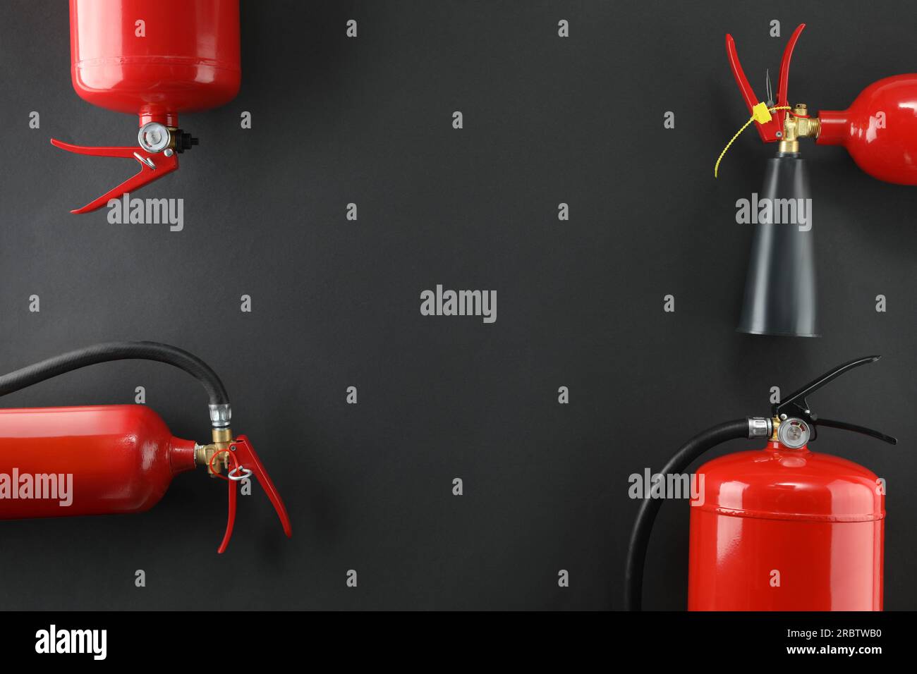 Different fire extinguishers on black background, flat lay. Space for ...