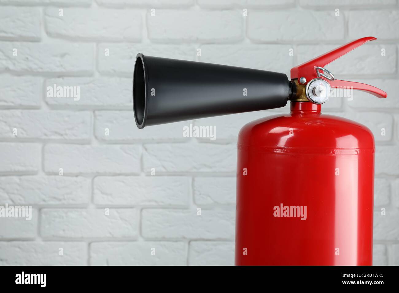 Fire extinguisher against white brick wall, closeup Stock Photo - Alamy