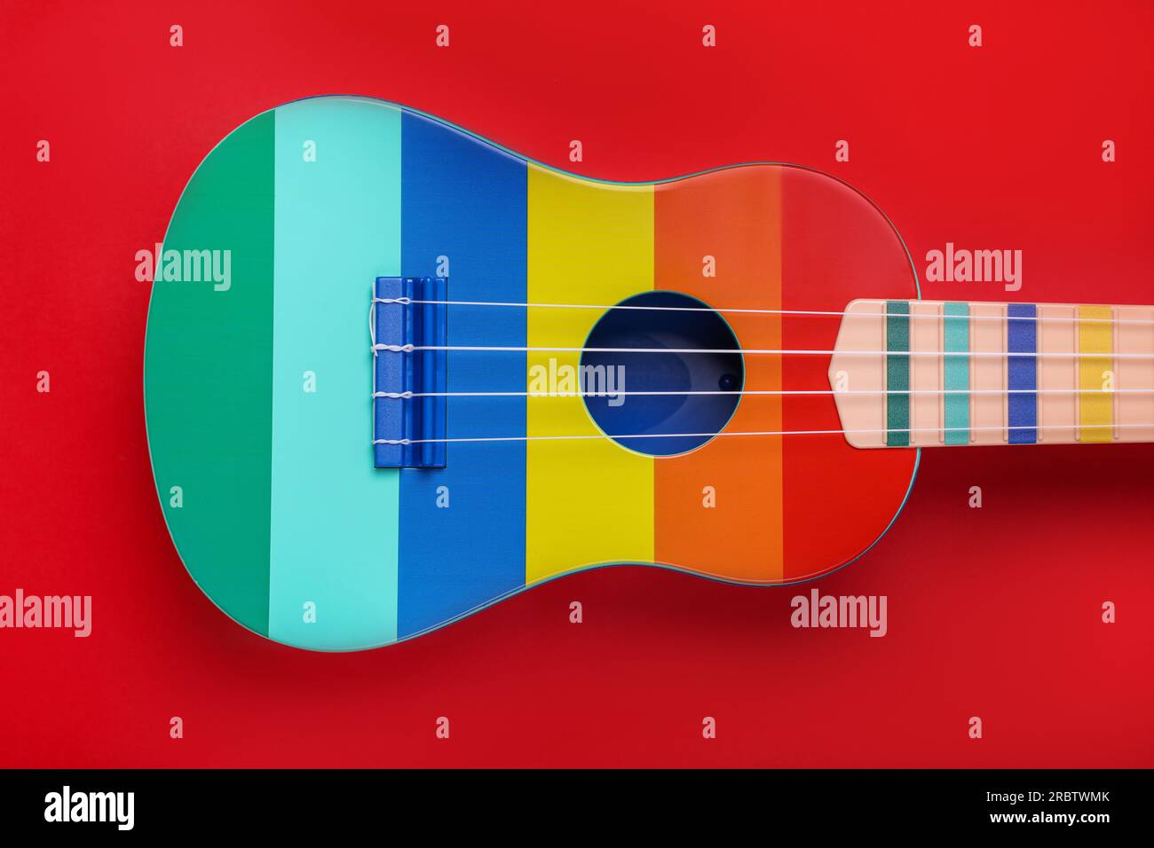Colorful ukulele on red background, top view. String musical instrument ...