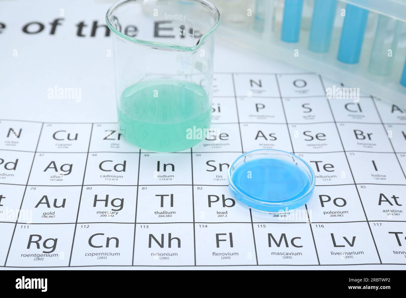 Beaker and Petri dish on periodic table of chemical elements, closeup ...