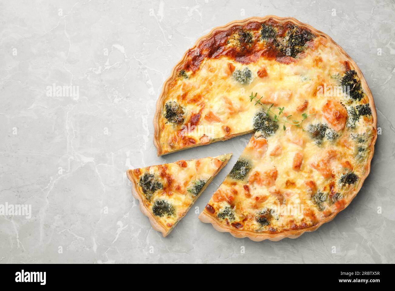Delicious homemade quiche with salmon and broccoli on light gray marble ...