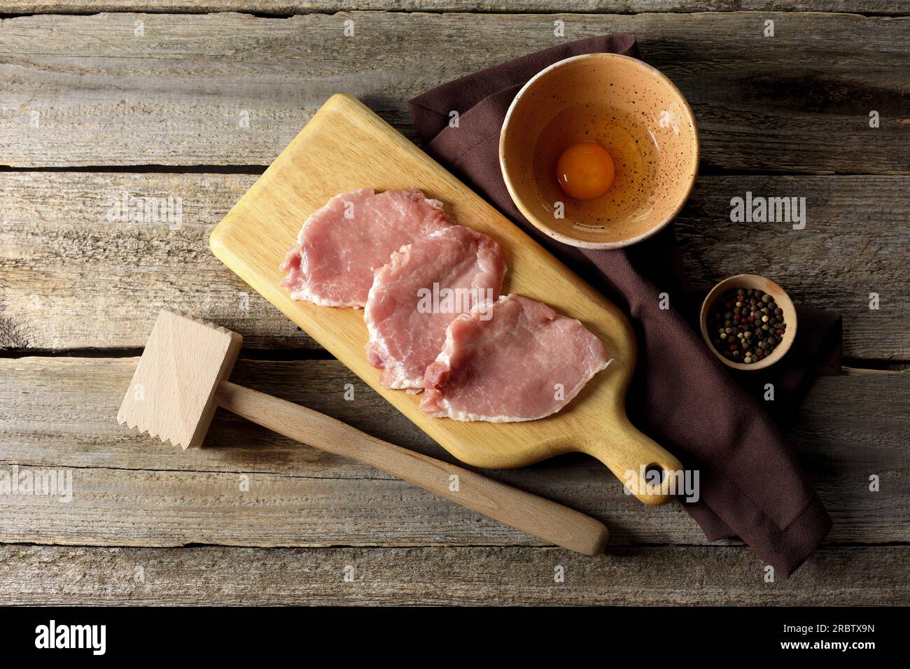 Cooking schnitzel. Raw pork slices, egg, peppercorns and meat ...