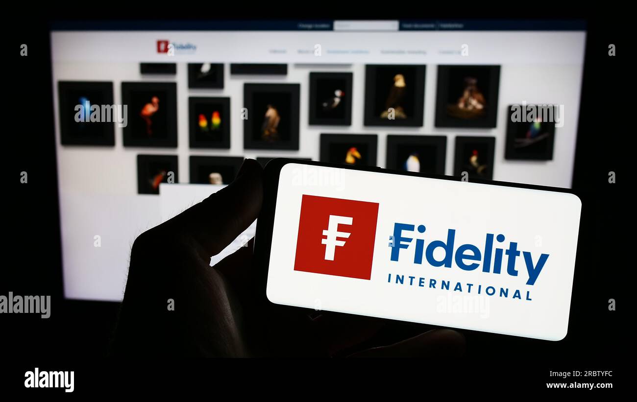 Person holding mobile phone with logo of financial company Fidelity International Ltd. on screen ...
