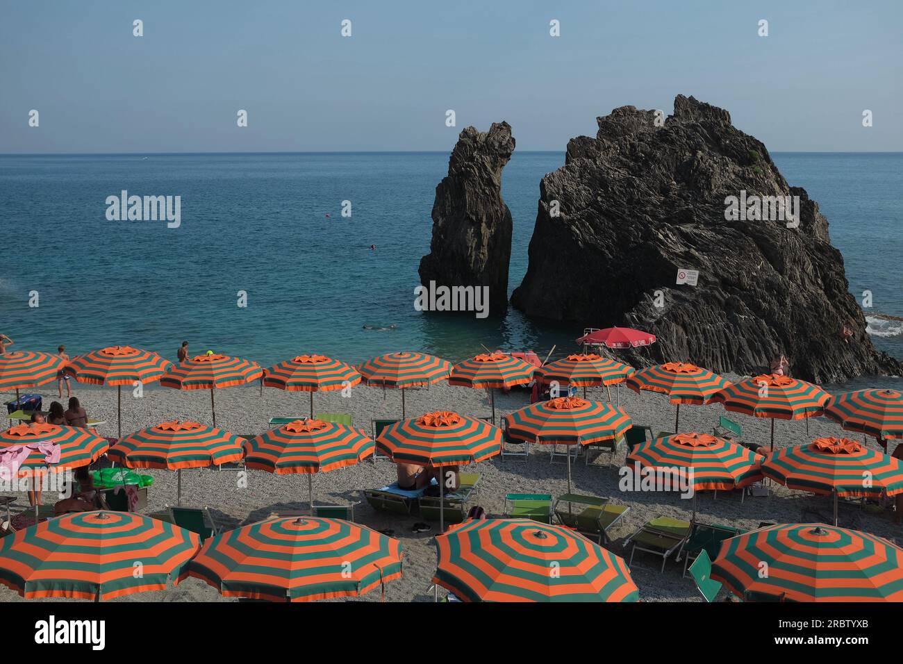 Cinque Terre, Italy - tourists relax under orange and green beach ...
