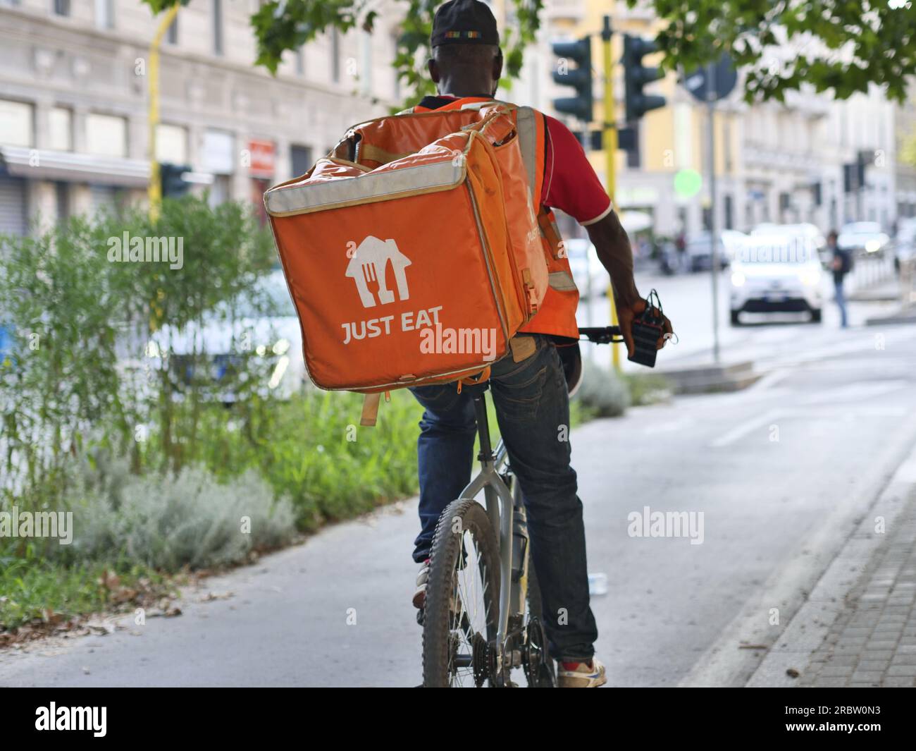 Bicycle food delivery rider working in the street of Milan before ...