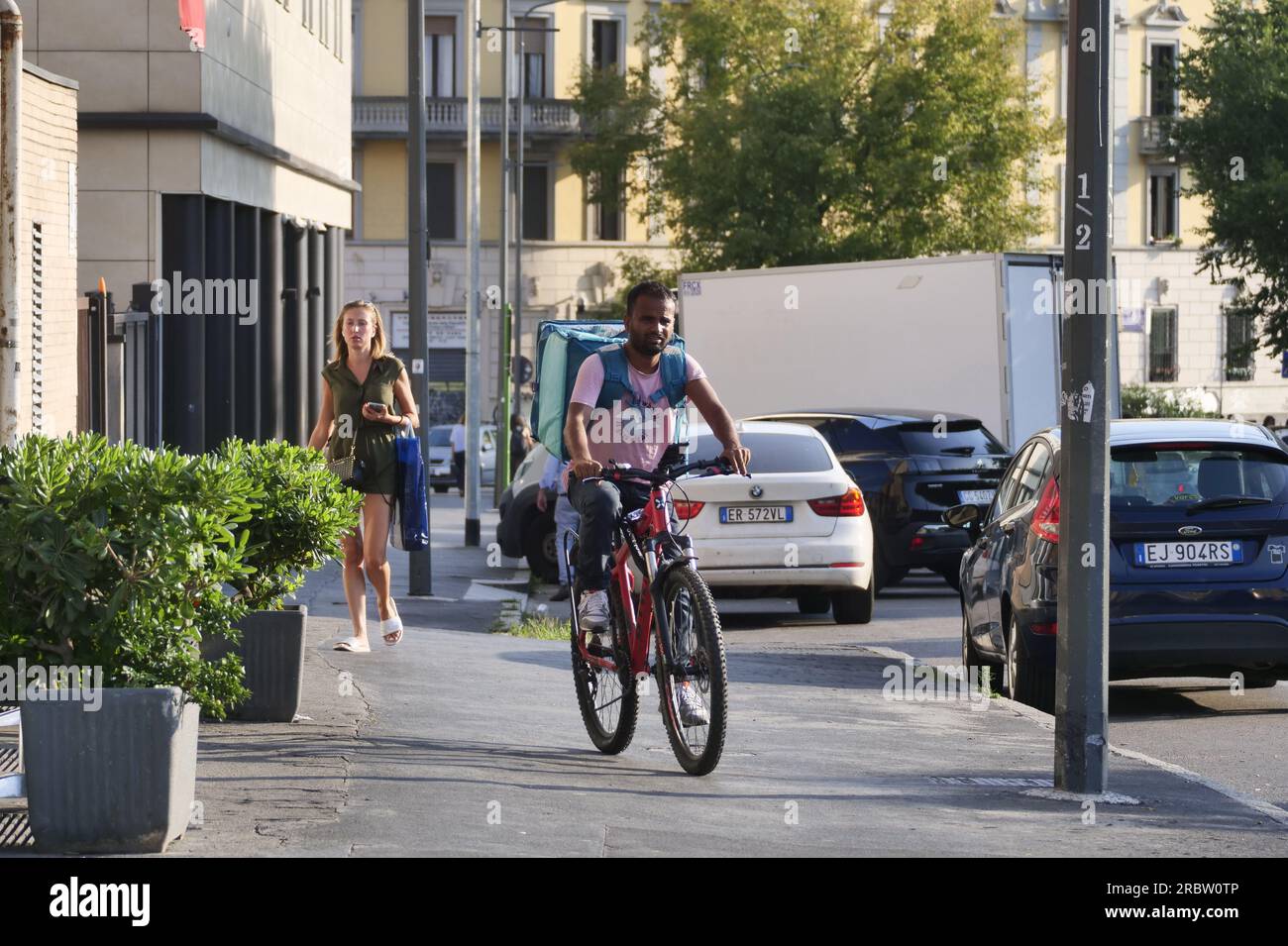 Bicycle food delivery rider working in the street of Milan before ...