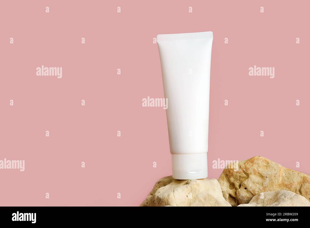 White cosmetic products tube on rock isolated on pink background ...