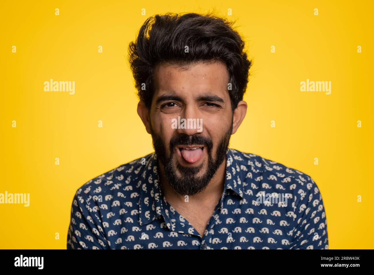 Young indian man showing tongue making childish faces at camera ...