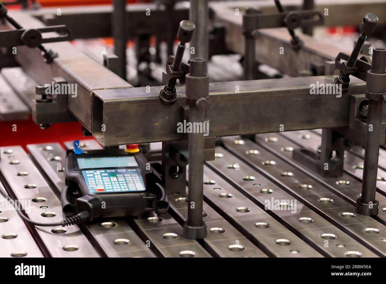 Workpieces and handheld CNC welding robot controller on welding table ...