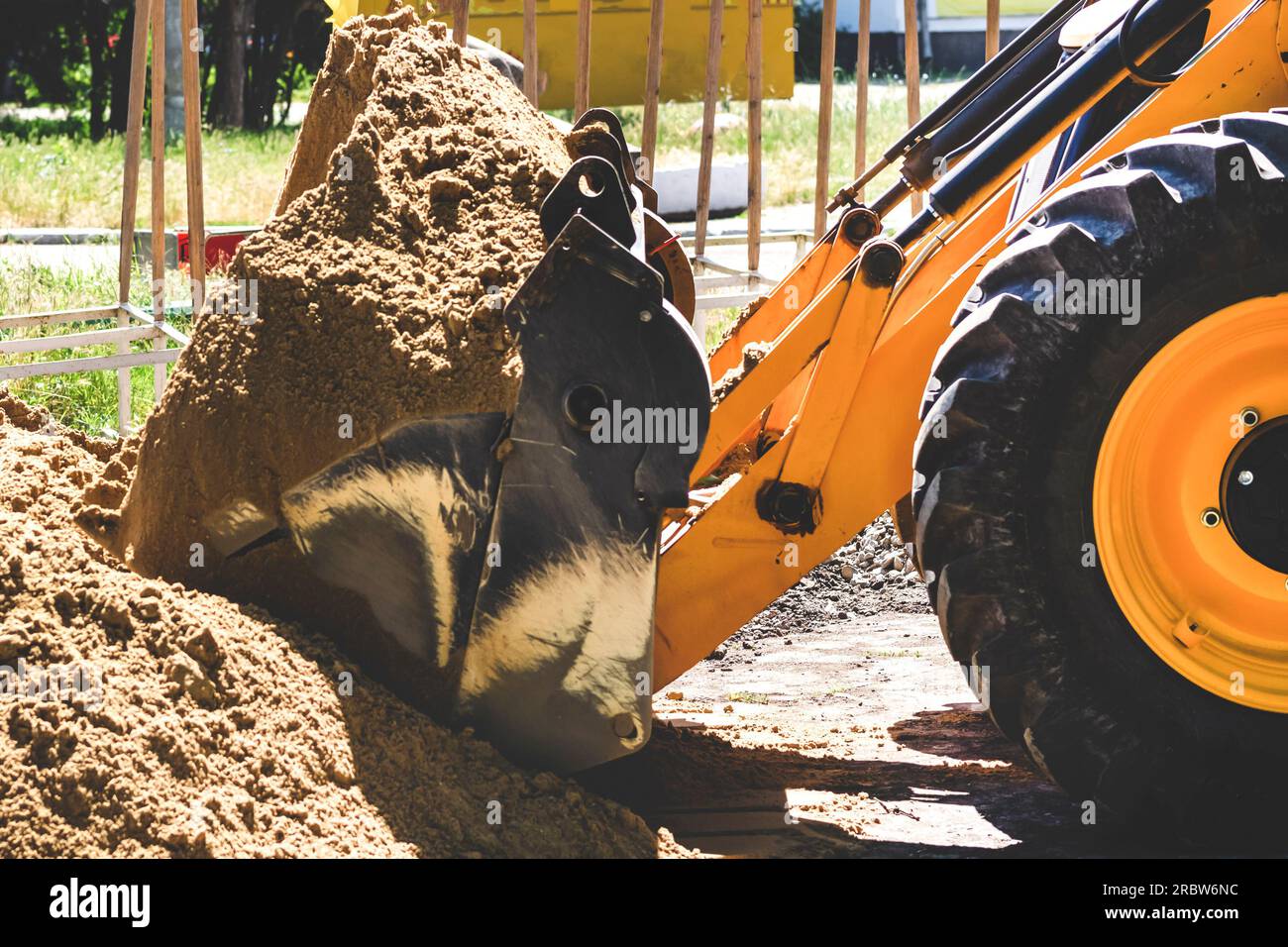 The tractor is rowing sand. Excavator bucket with sand. Road ...