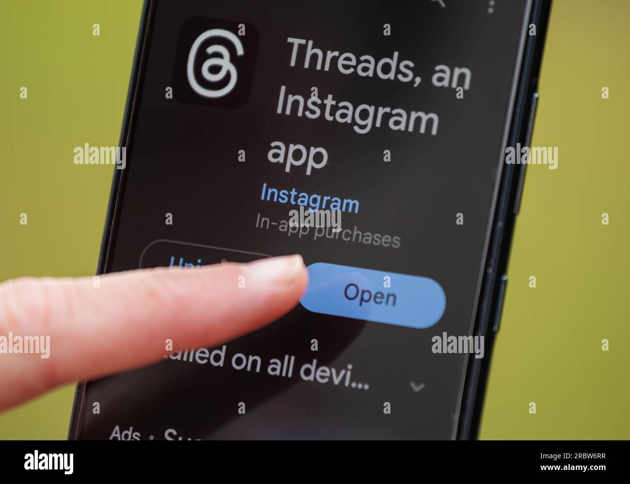 Finger pressing open button on smartphone touchscreen to open the new Instagram Threads app, a ...