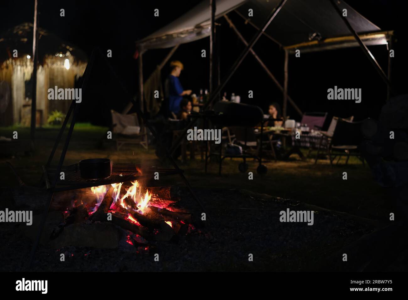 Burning bonfire near camping tent outdoors in evening and group of ...