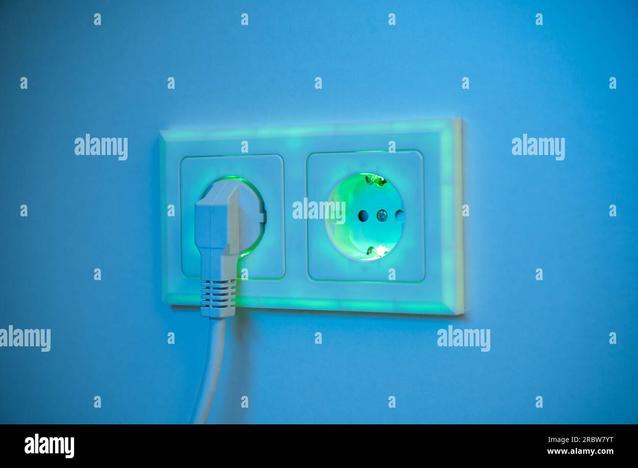 Green illuminated socket with plug inserted to symbolise power ...