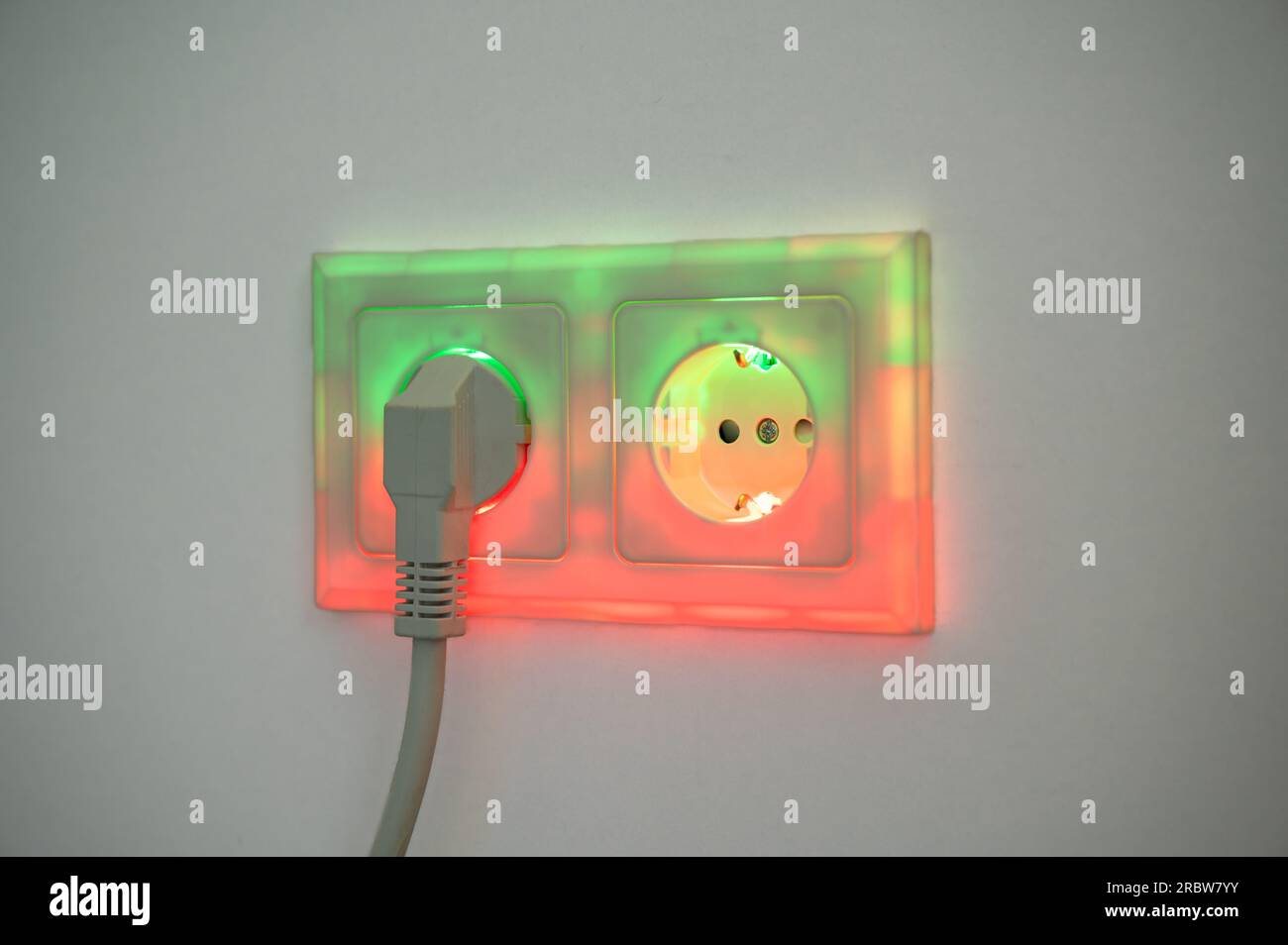 Red and green illuminated socket with plug inserted to symbolise power ...