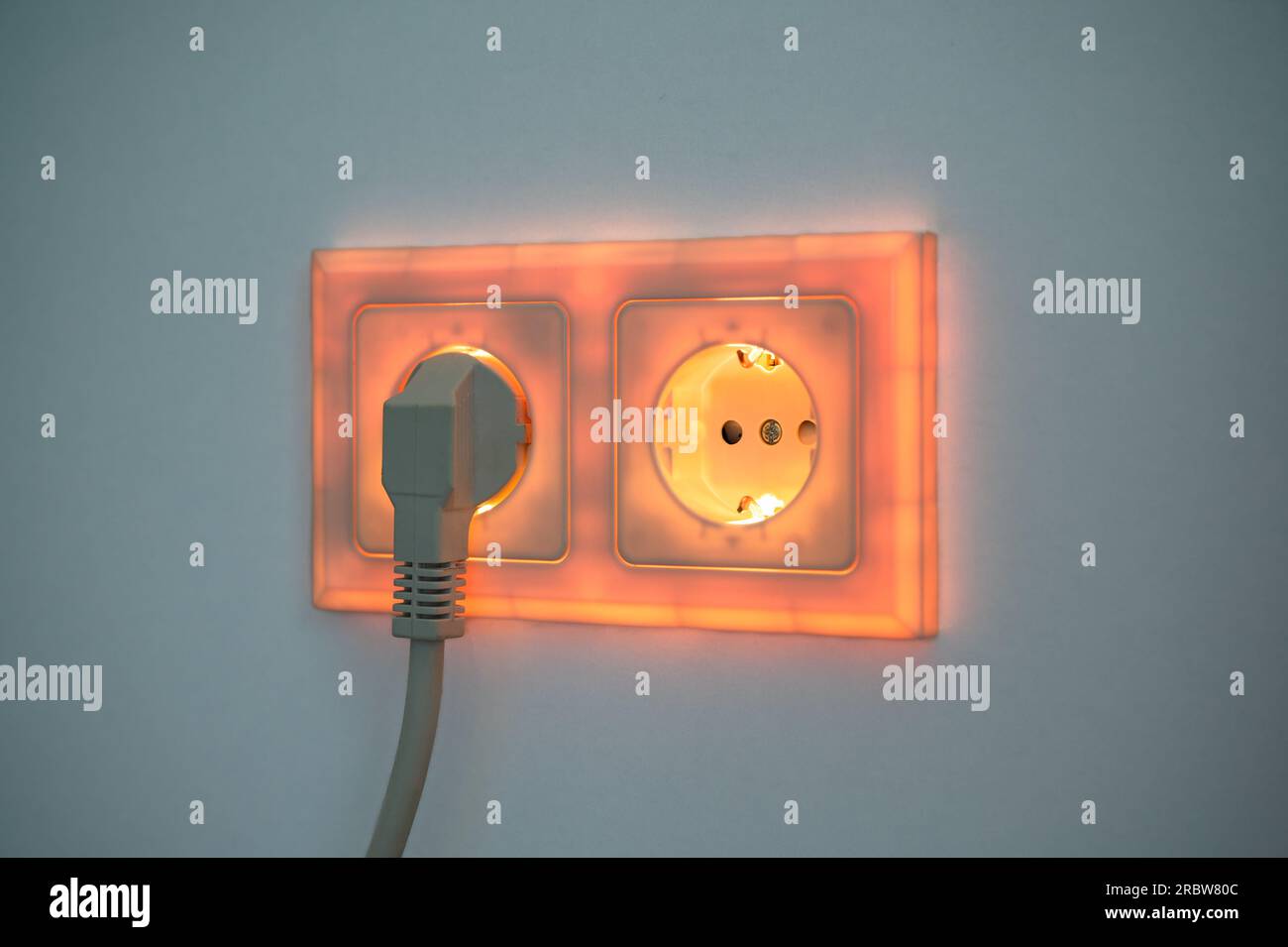 Yelow illuminated socket with plug inserted to symbolise power ...