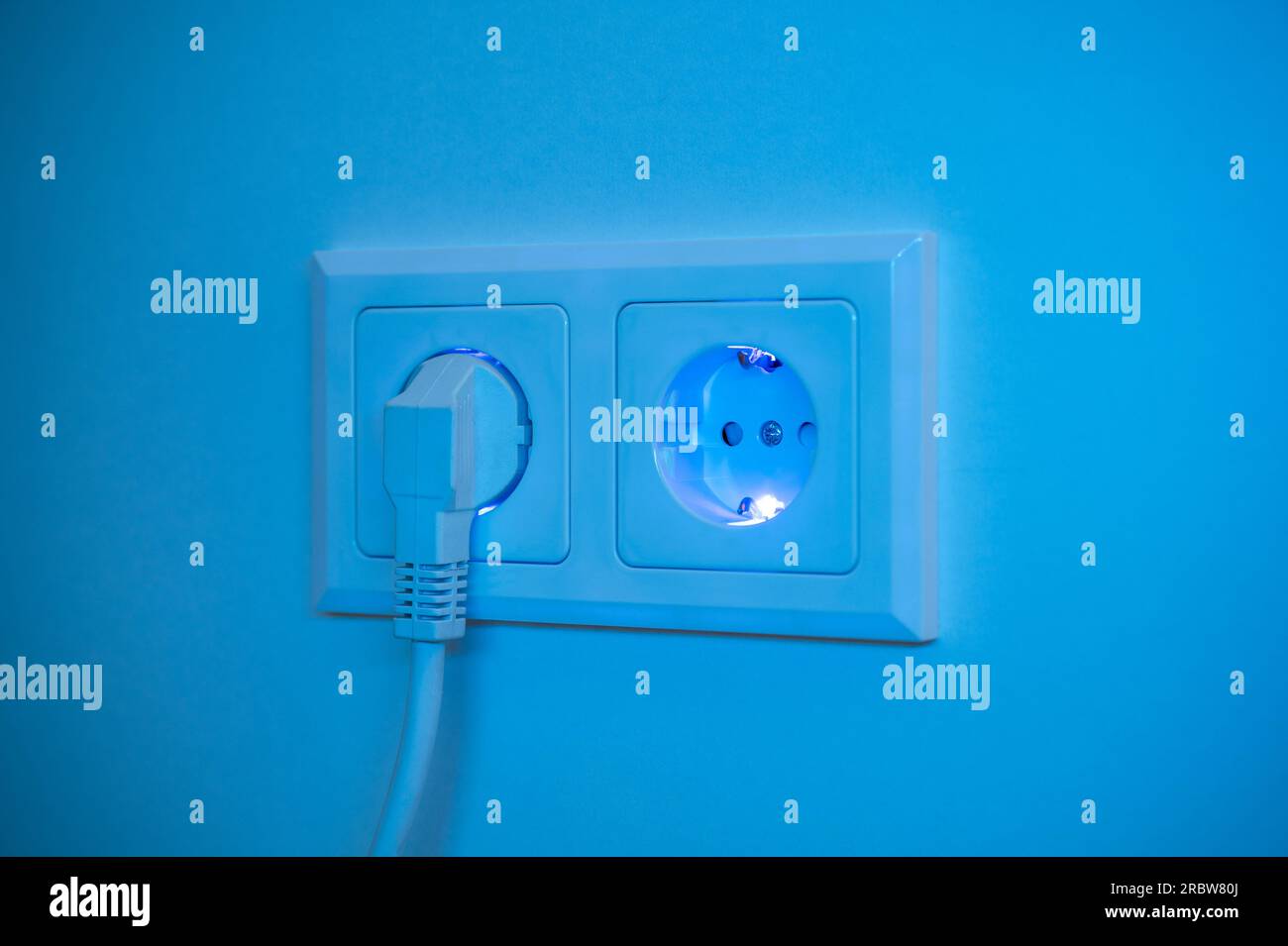 Blue illuminated socket with plug inserted to symbolise power ...
