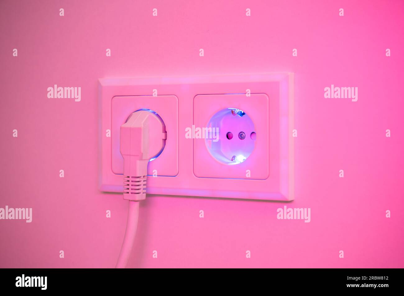 Blue and pink illuminated socket with plug inserted to symbolise power ...