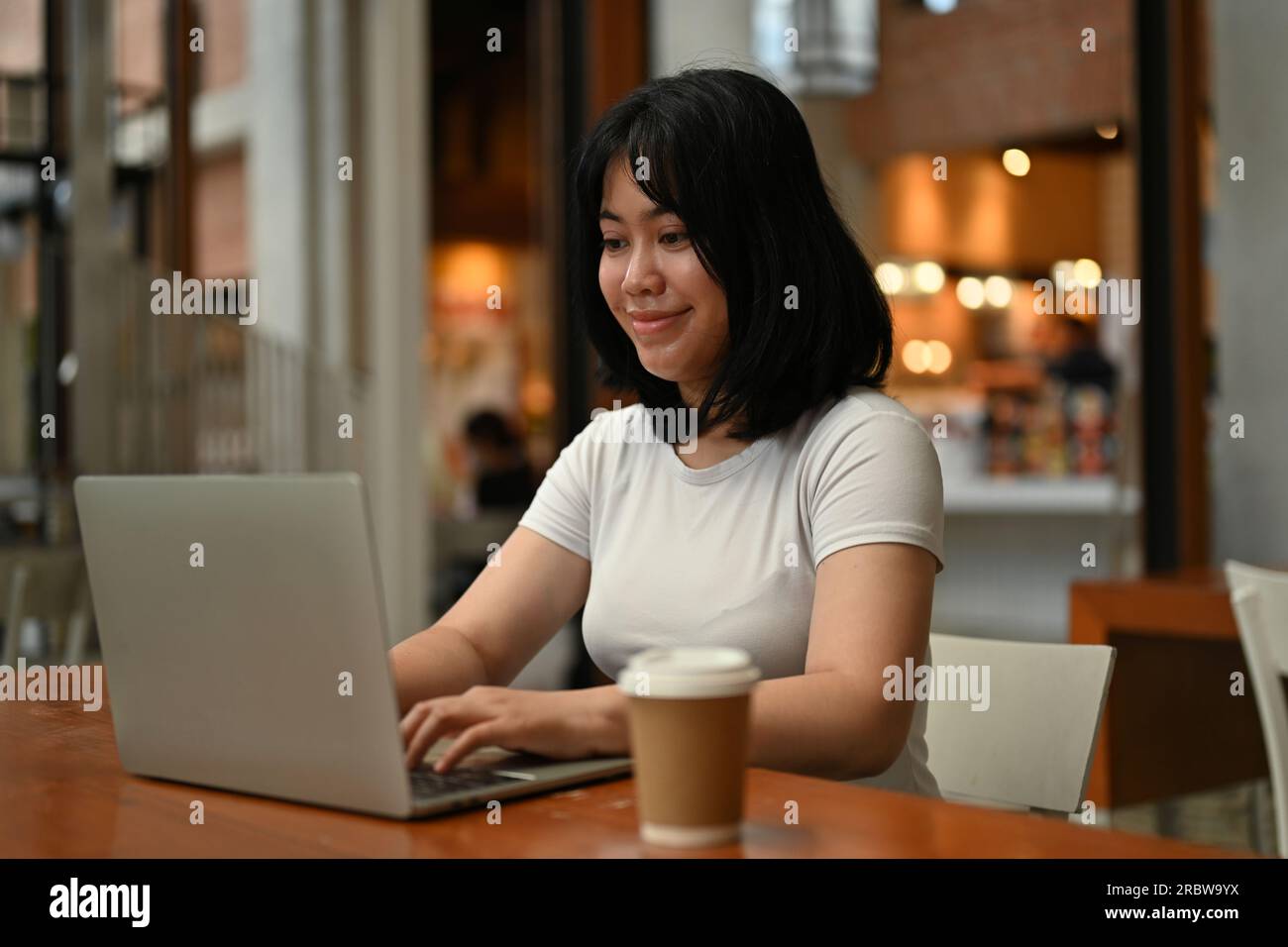 A beautiful young Asian female freelancer remote working at a coffee ...