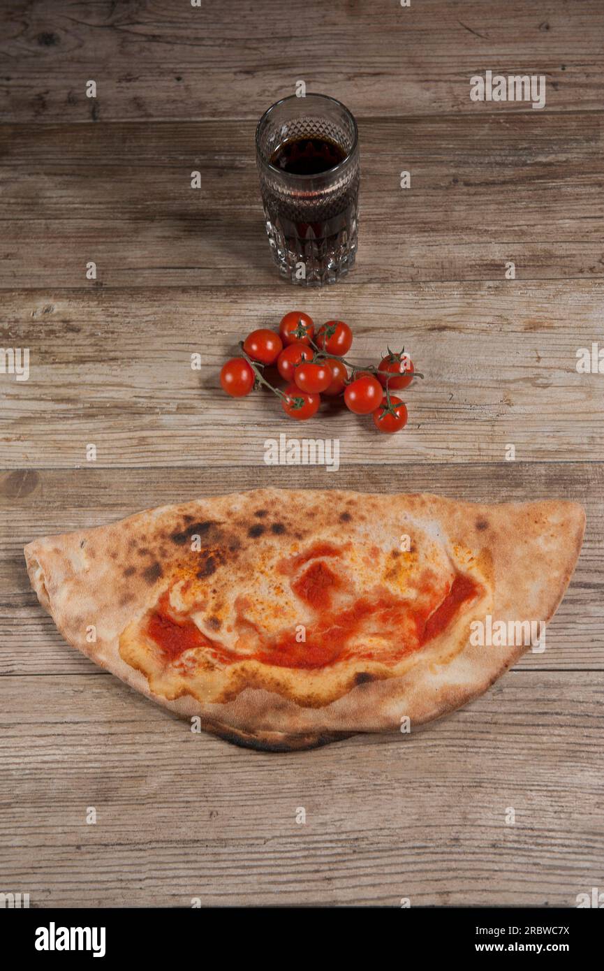 Calzone, Tipica pizza italiana. Typical Pizza stuffed with mozzarella cheese, ham and tomato ...