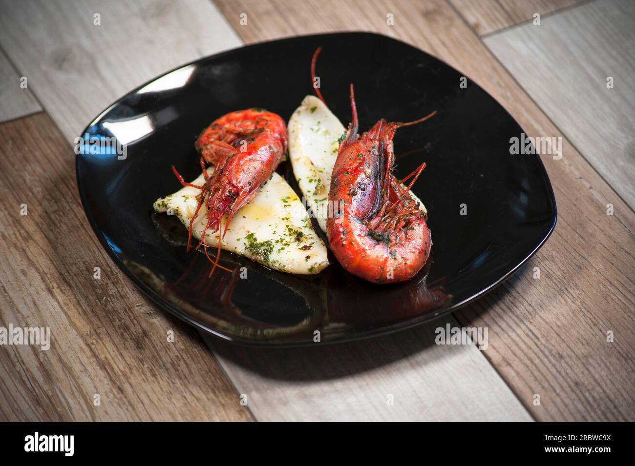 Red prawns and squid grilled seared with olive oil, garlic and parsley Stock Photo - Alamy