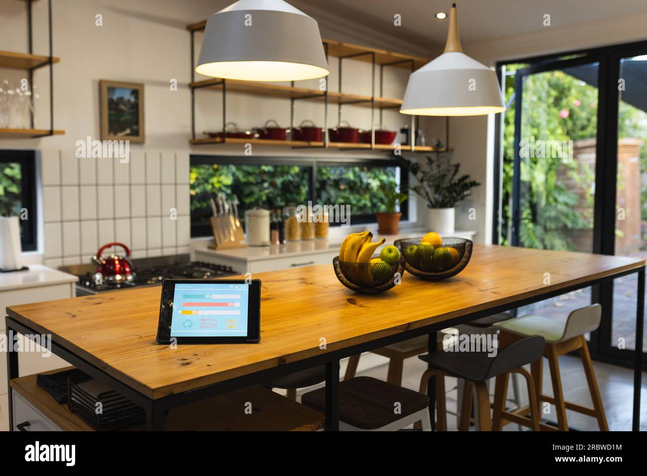 Tablet with smart home interface on wooden island countertop in kitchen ...