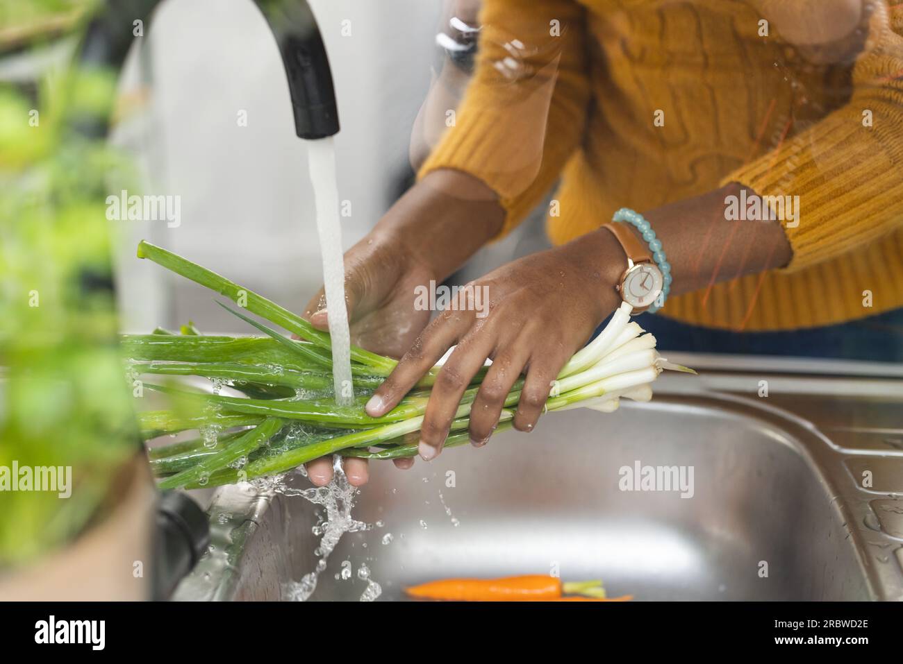 Mid section of african american woman rinsing vegetables in kitchen ...